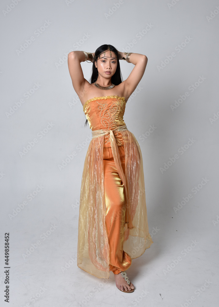 Full length portrait of pretty young asian woman wearing golden Arabian ...