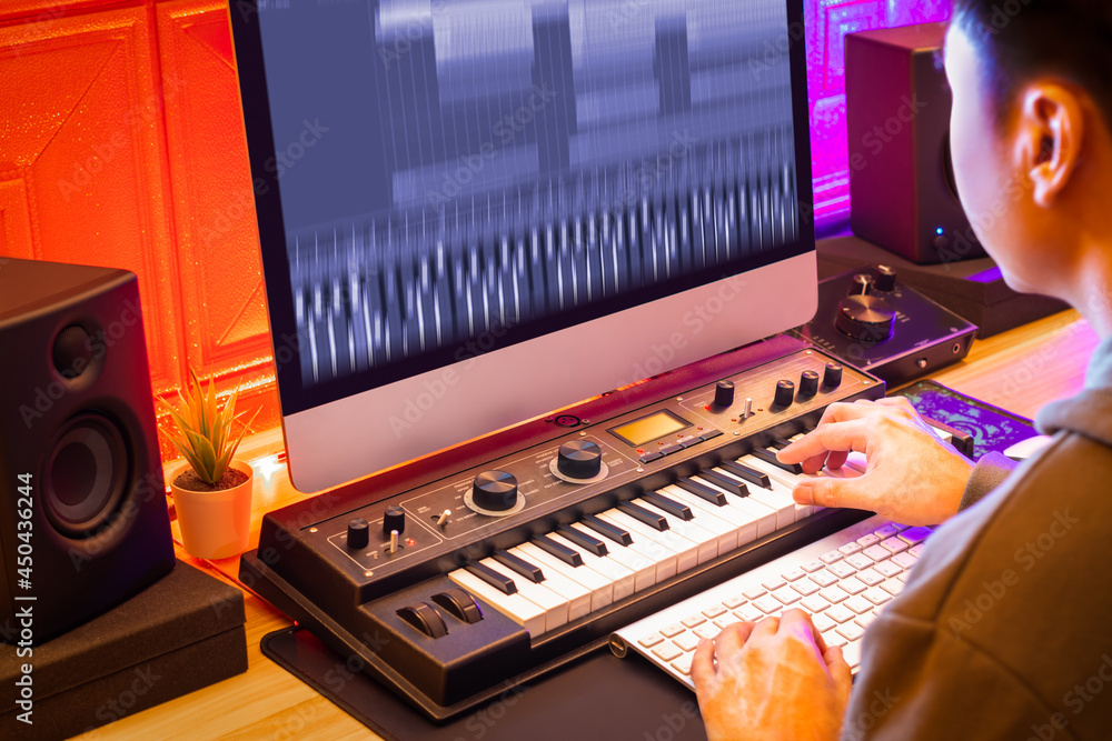 asian male professional music producer recording midi track on keyboard ...