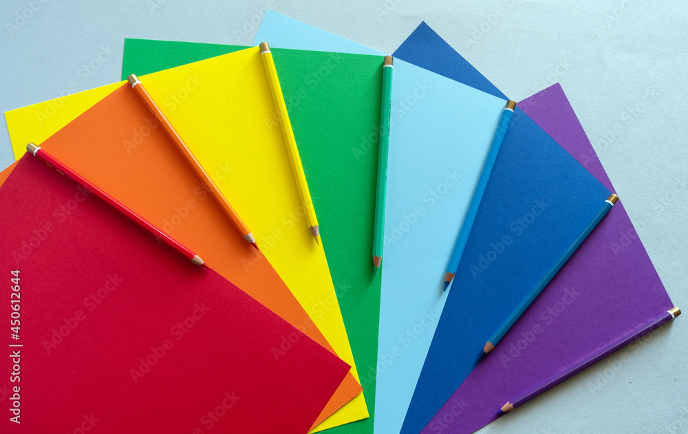 Sheets of multi-colored paper with colored pencils to match the paper ...