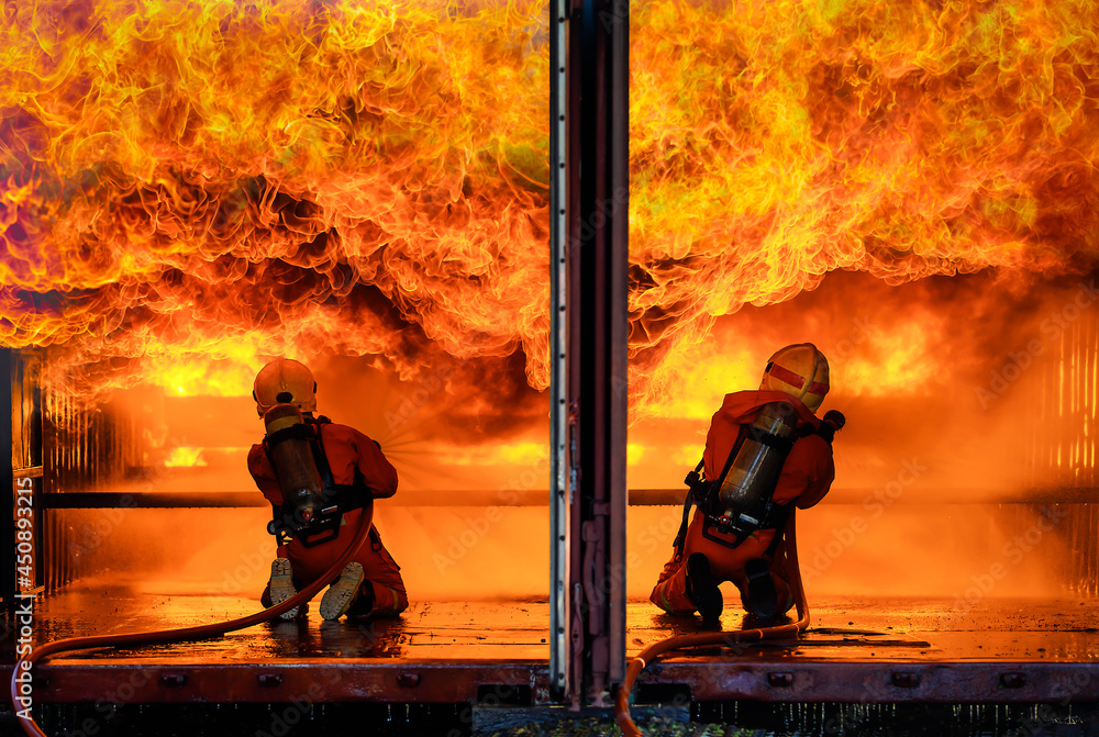 Team of two firefighters wearing full uniform with oxygen tank on back ...