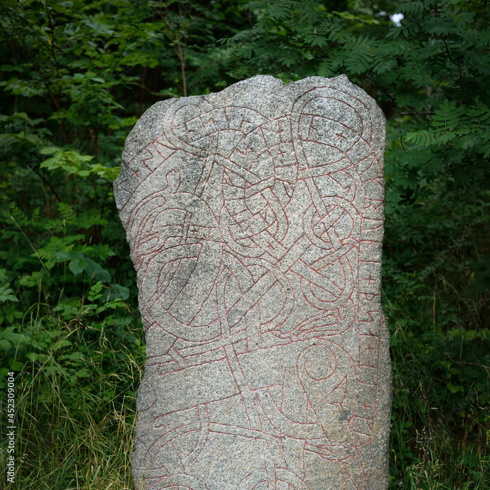 Ancient stone with runes in a green summer park. Enköping, lake Mälaren ...