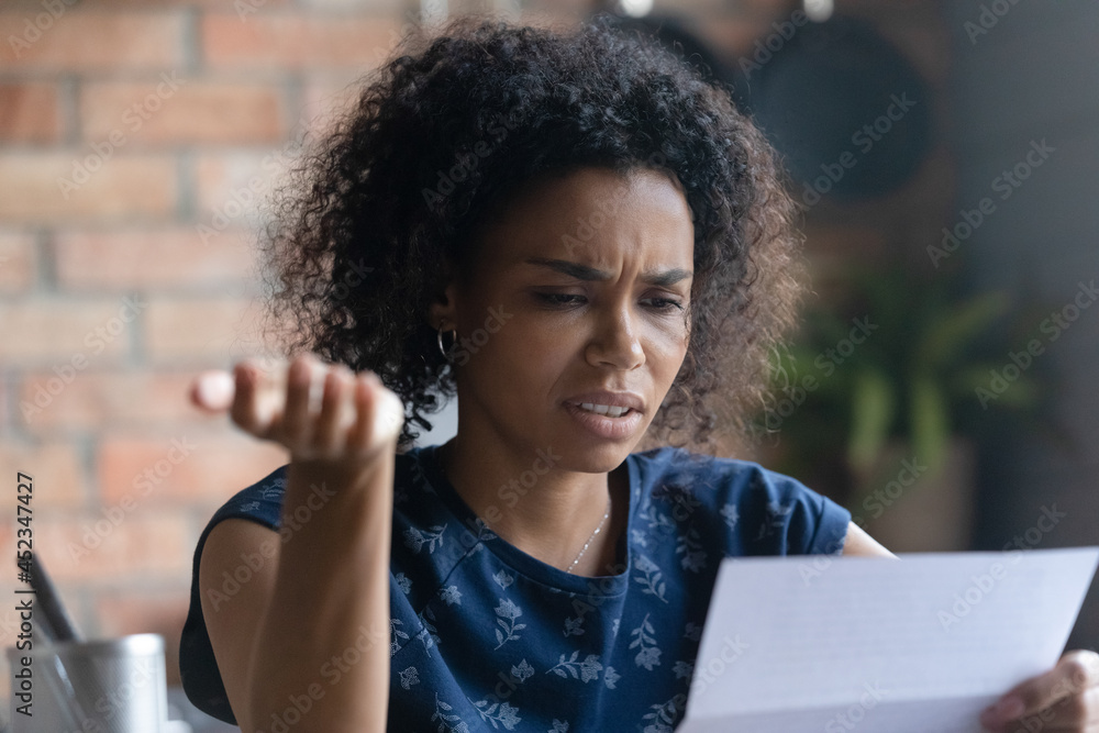 Frustrated millennial young Black woman reading paper letter with bad ...