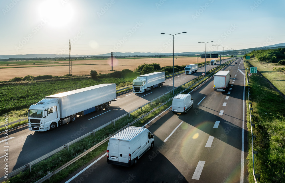 Convoy or caravans of transportation trucks passing vans and truck on a ...