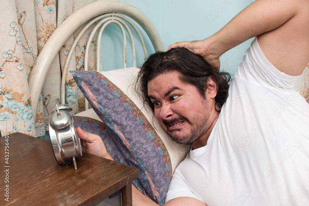 Foto de Stock A man lying in bed is furious at the loud ringing of an ...