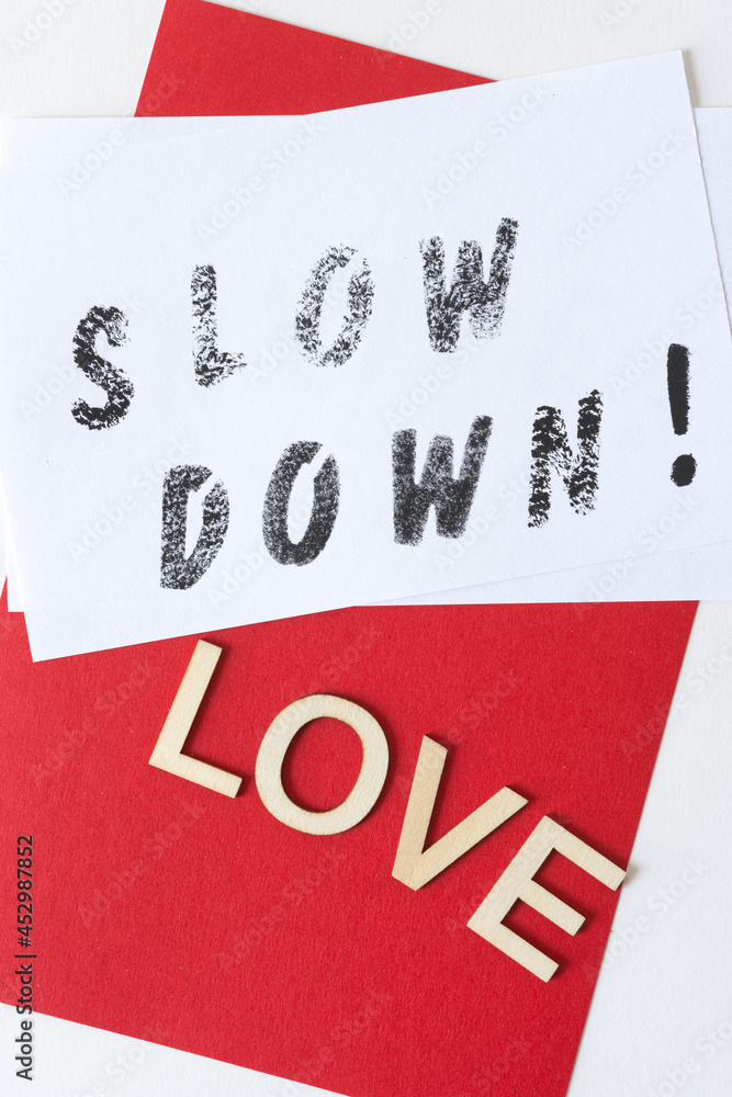 the expression "slow down!" stencilled in black on white paper, with ...