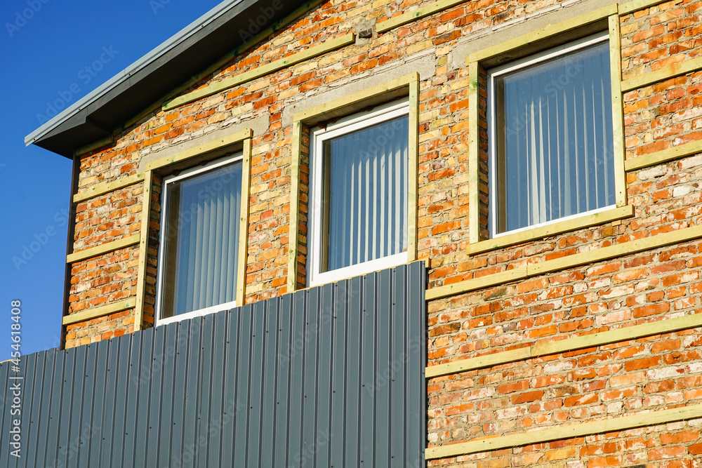 cladding of a brick house facade with corrugated sheet metal Stock ...
