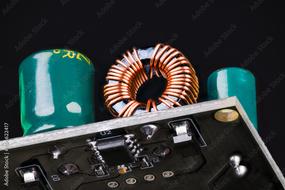 Printed circuit board with toroidal coil or green capacitors on black ...