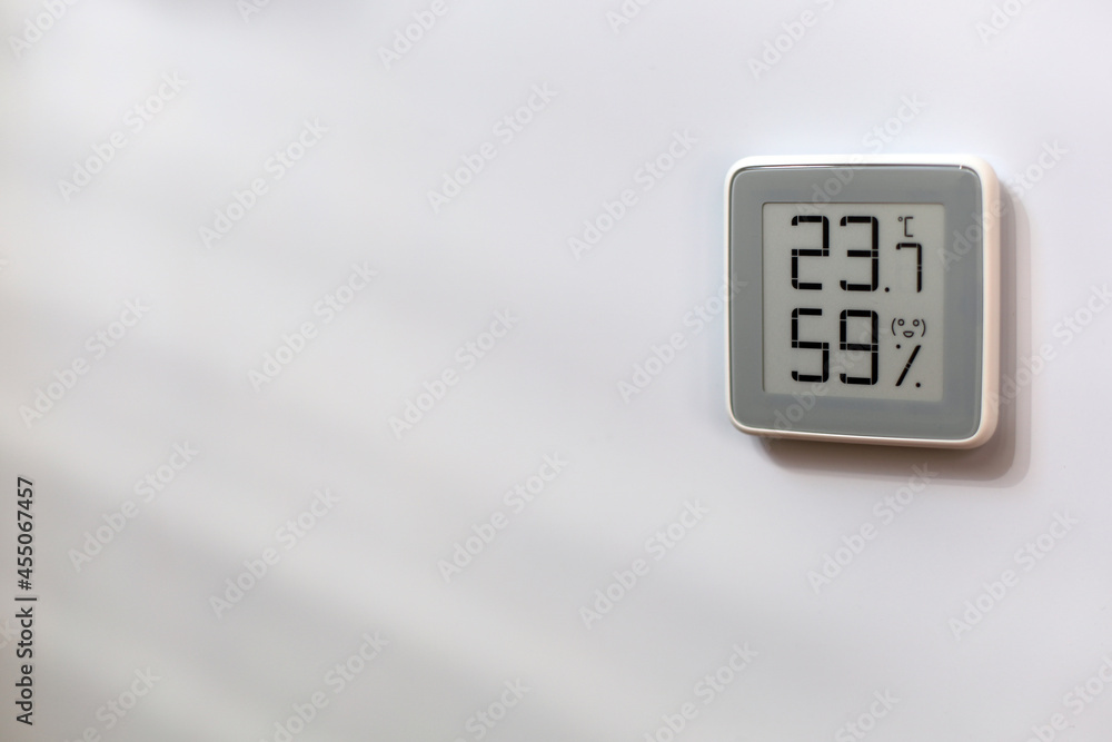 Indoor gray plastic digital thermometer on white wall showing ...