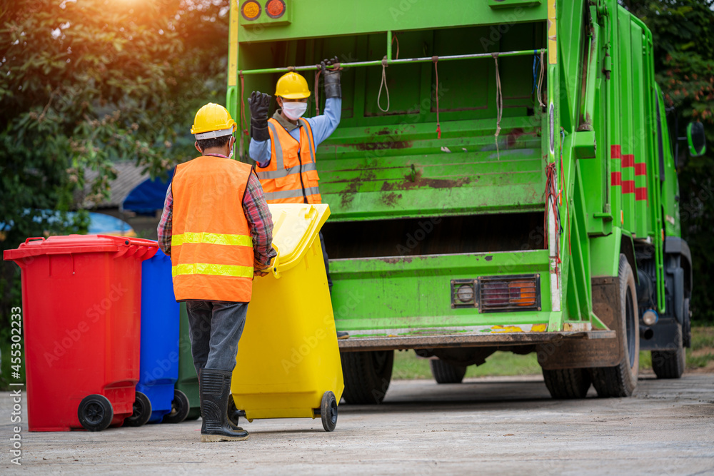 Rubbish cleaner man working with green garbage truck loading waste and ...