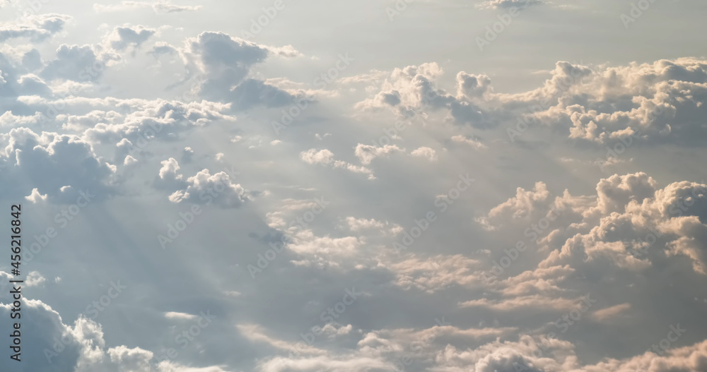 Flying high above gray cloudscape backlit by sun rays, view from ...