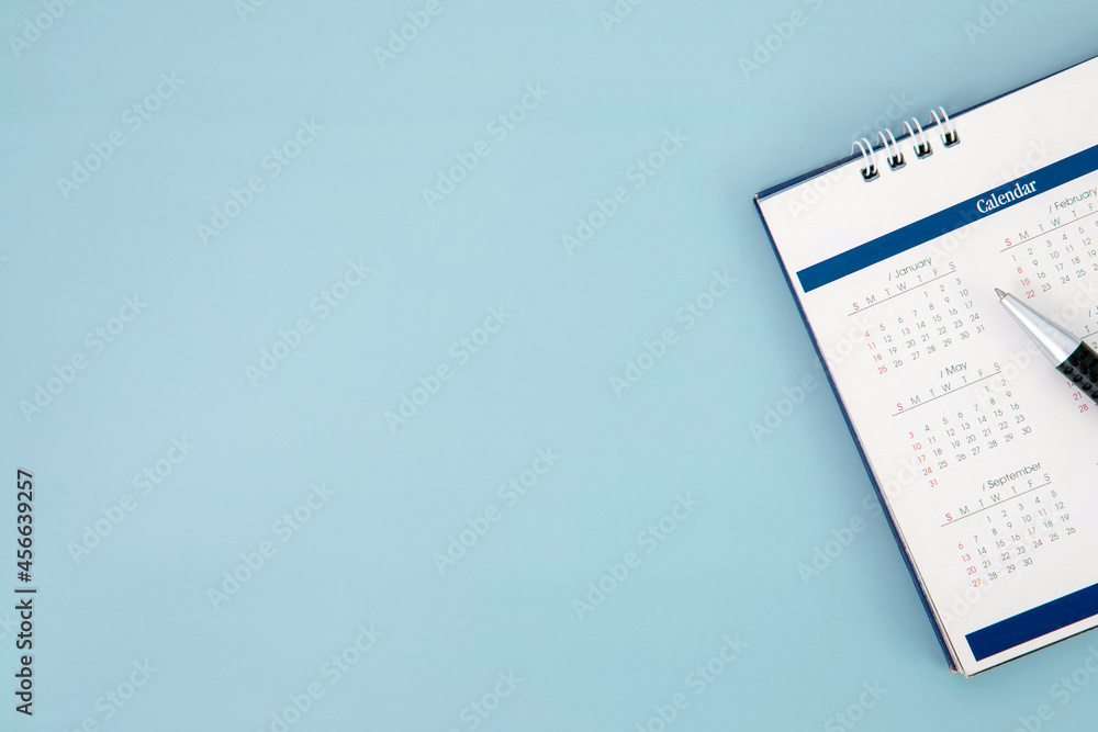 pen and calendar placed on blue background with copy space, business ...
