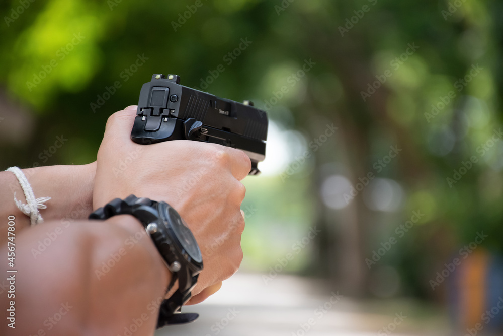 Automatic black 9mm pistol holding in hands aming to the shooting tar ...