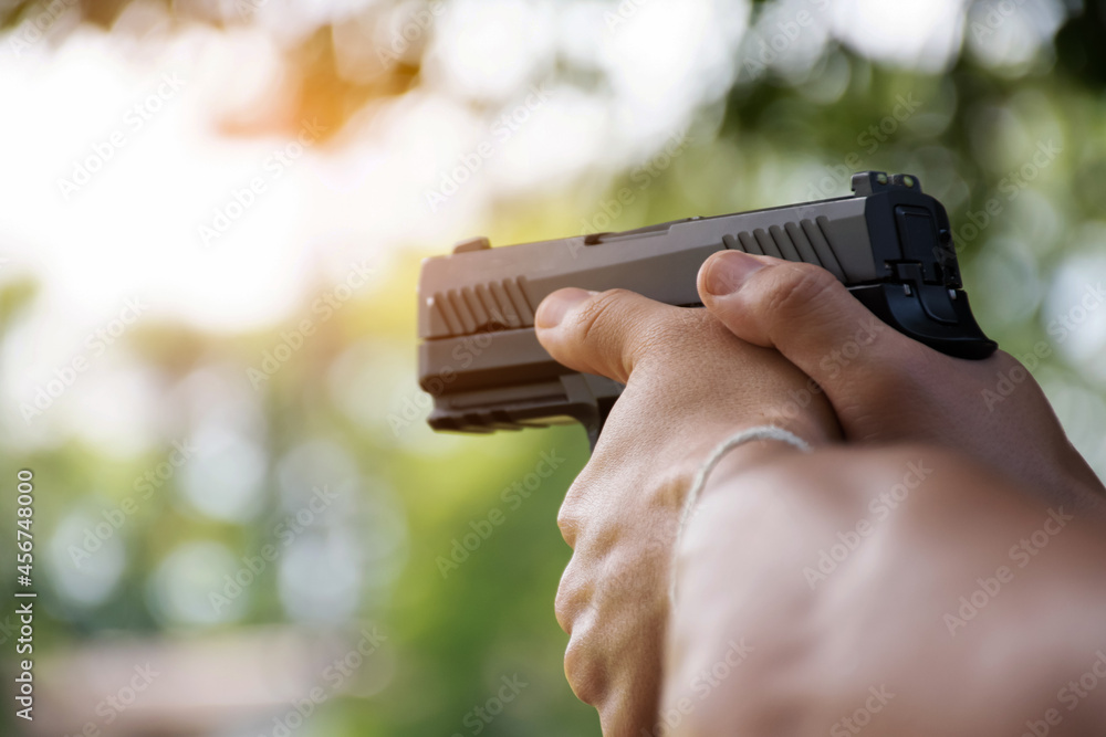 Automatic black 9mm pistol holding in hands aming to the shooting tar ...