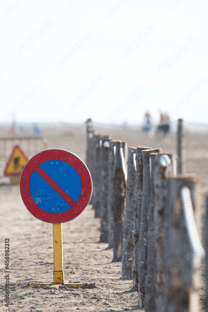 Vertical image of a no parking traffic sign on a beach with a wooden ...
