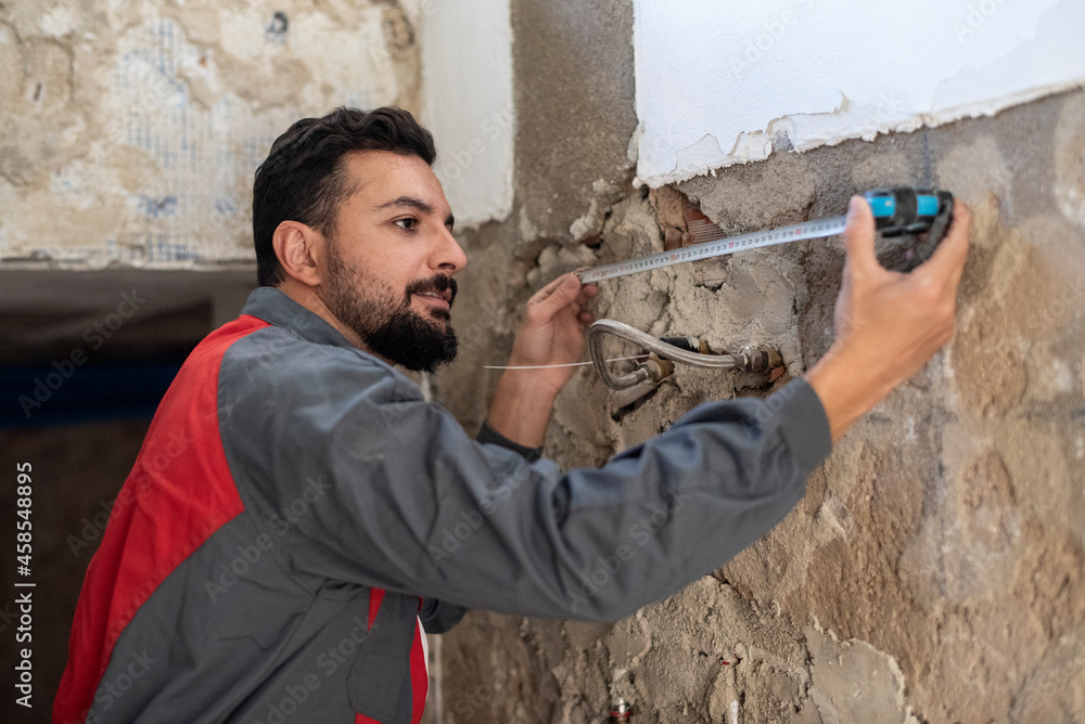 Plumber with tape measure measures the distance between pipes to avoid ...