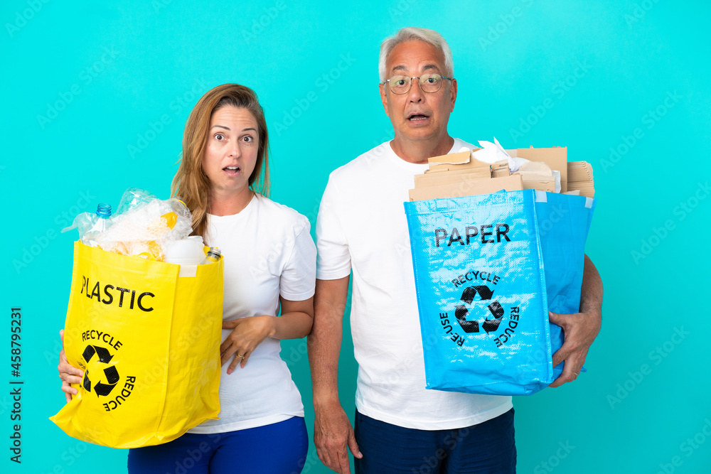 Middle age couple holding a recycling bags full of paper and plastic ...