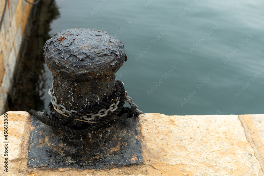 bollard or cast iron and steel mooring bollard on the edge of a harbor ...