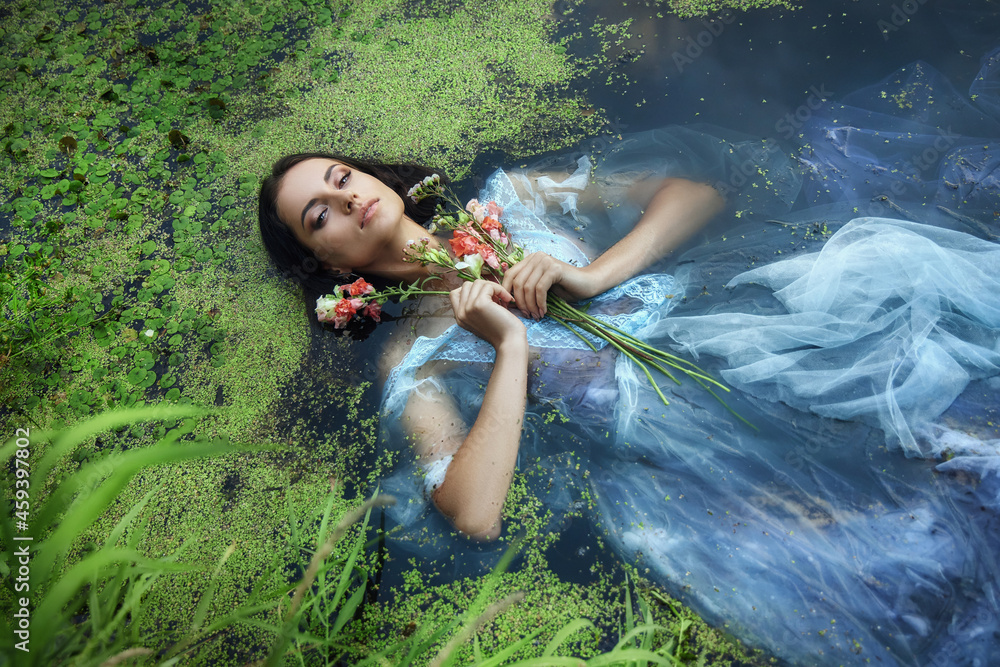 Art beautiful romantic woman lies in swamp in blue long dress with ...