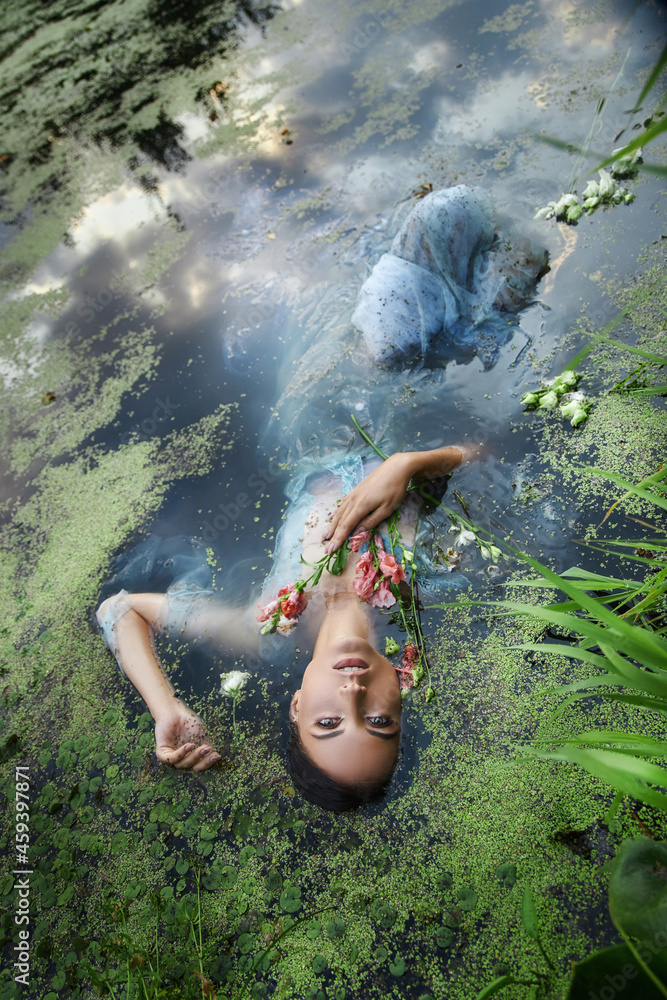 Art beautiful romantic woman lies in swamp in blue long dress with ...