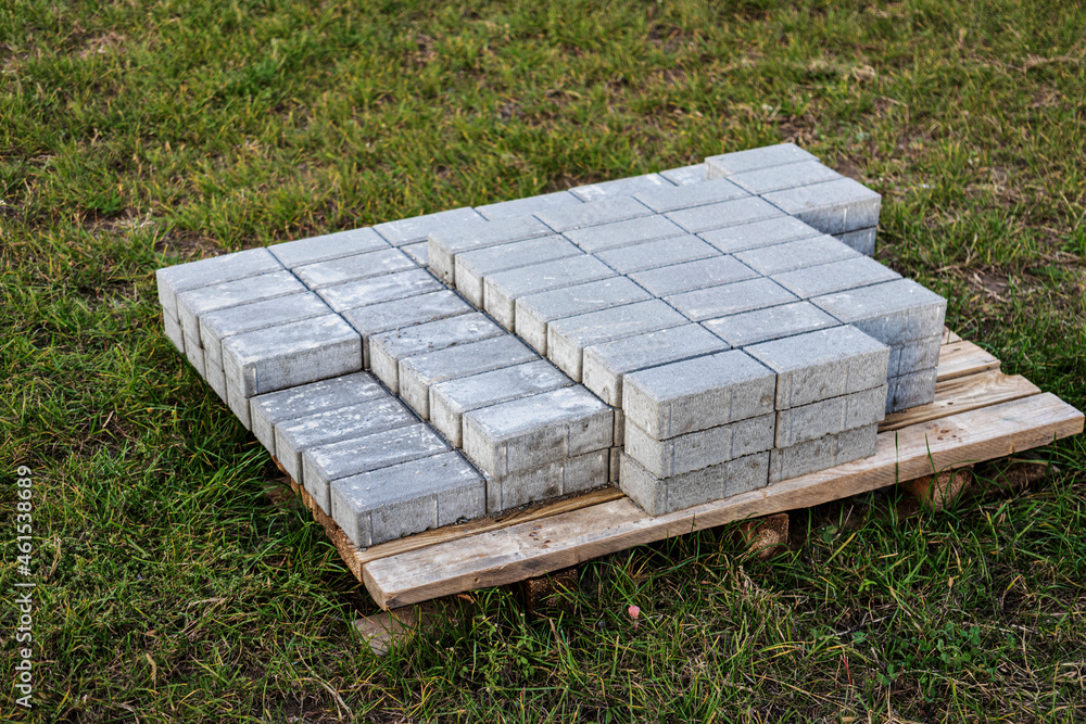 Paving slabs on a pallet prepared for installation on a green lawn ...