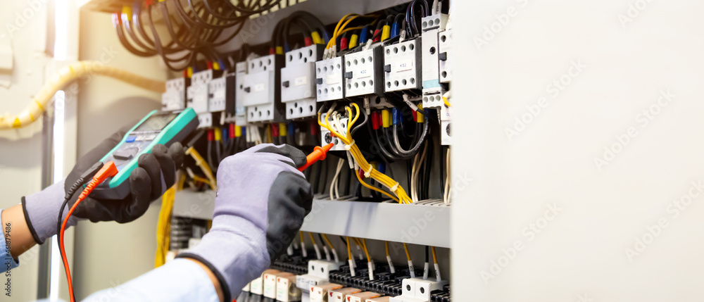 Electrical engineer using digital multi-meter measuring equipment to ...