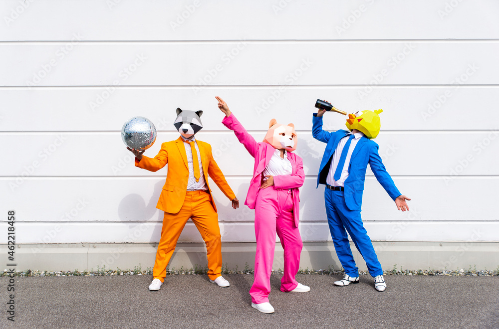 Three people wearing vibrant suits and animal masks partying in front ...