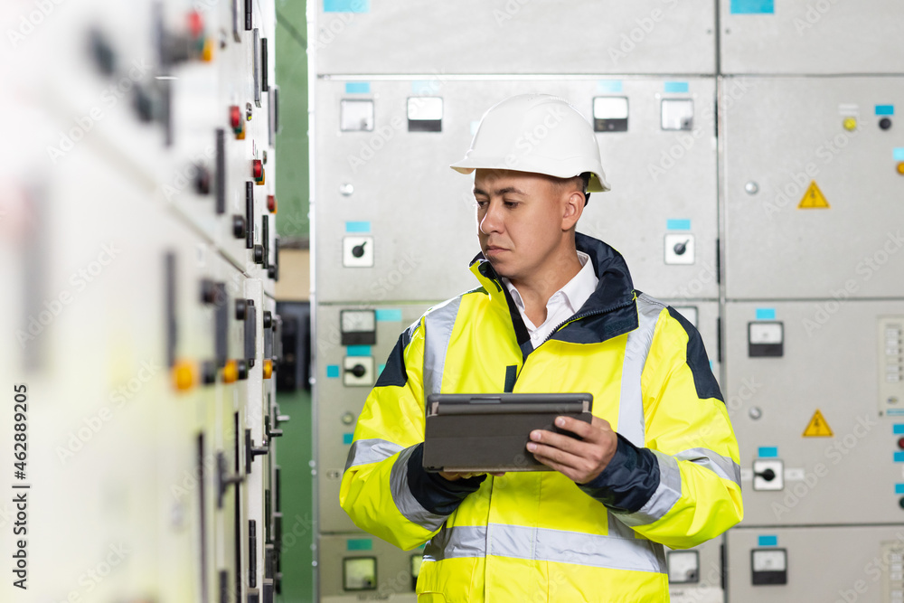 Asian man electrical engineer hold tablet monitoring electrical system ...