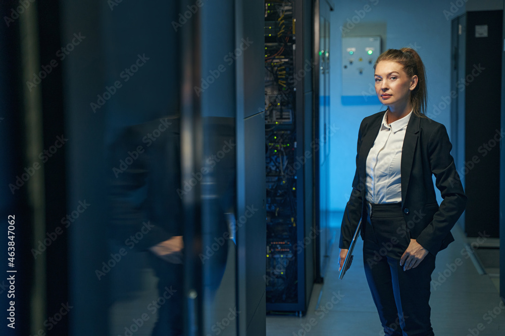 Confident woman engineer standing near server racks in datacenter Stock ...