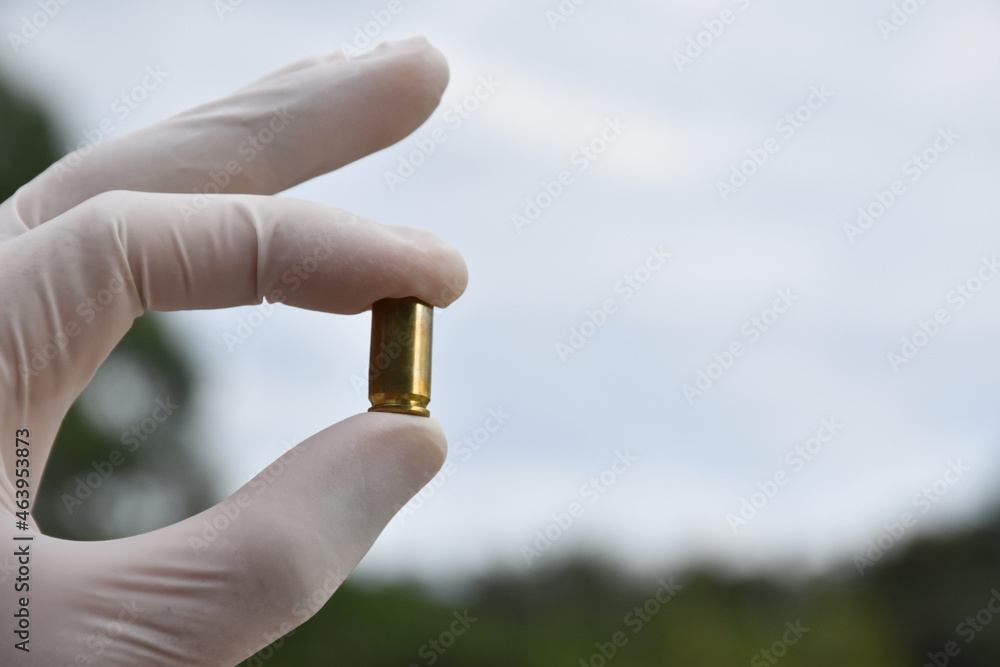 Forensic officers holds physical evidence which is the bullet shell up ...