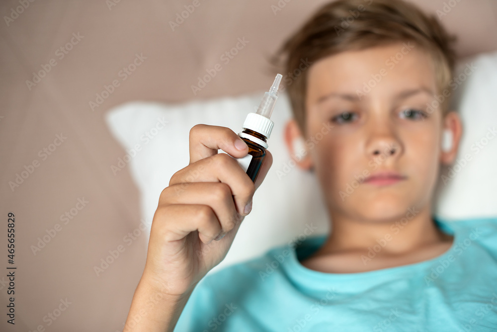 Teen boy with otitis and earaches holding drops for treatment. Kid ...