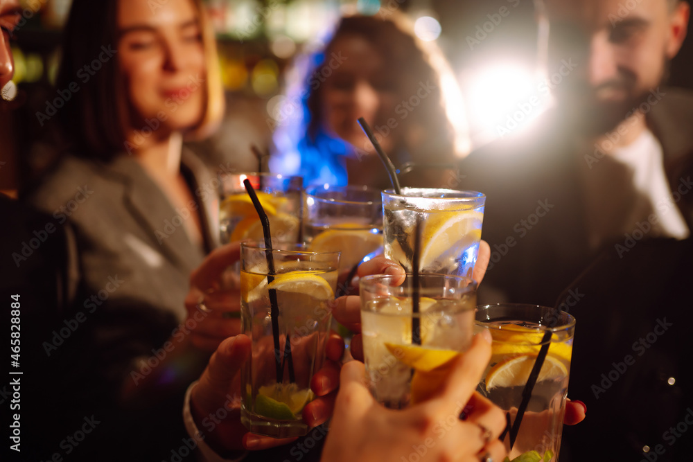 Cheering and drinking cocktails. Group of friends partying in a ...