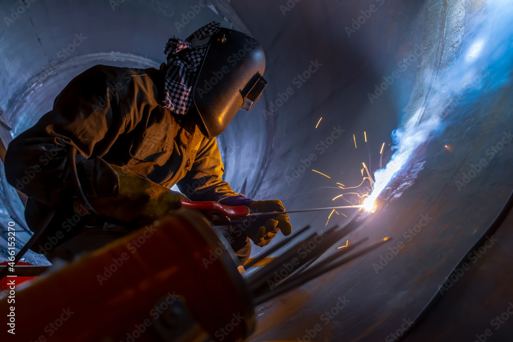 MMA welding. A welder welds large diameter pipes with manual electric ...