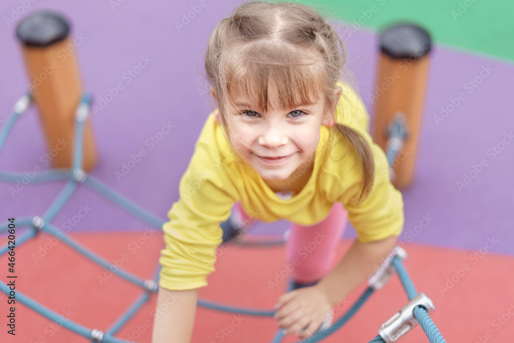 Cute little child girl having fun trying to climb on jungle gym at ...