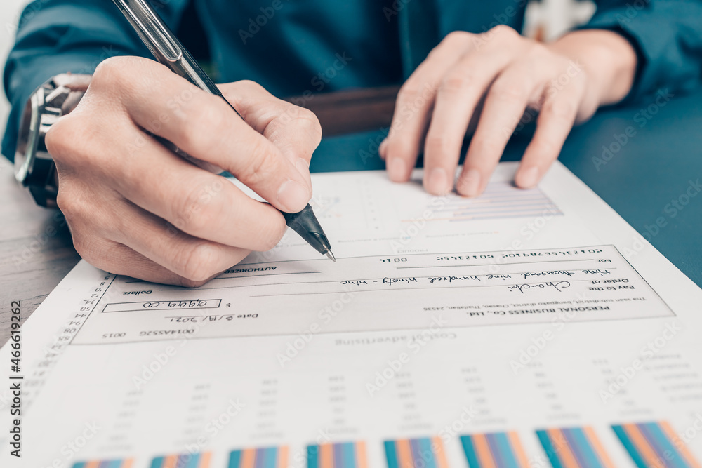 Business man hand writing and signing white blank bank check book and ...