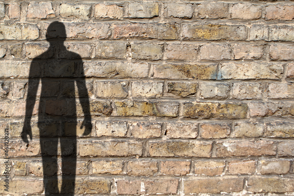 blurred black shadow of man on old brick wall background, concept of ...