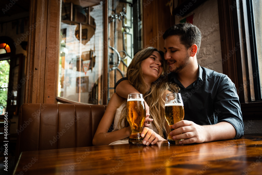 attractive young man and woman couple in love sitting down at pub ...