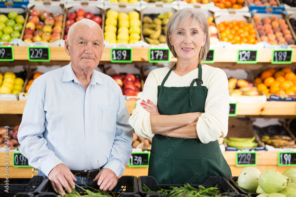 Woman supermarket worker and old man customer standing in salesroom of ...
