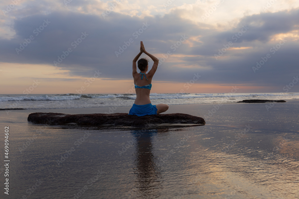 Sunset yoga. Caucasian woman sitting on the stone in Lotus pose ...