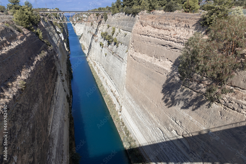 Deep narrow channel cut through the rock with old bridge and shadow of ...