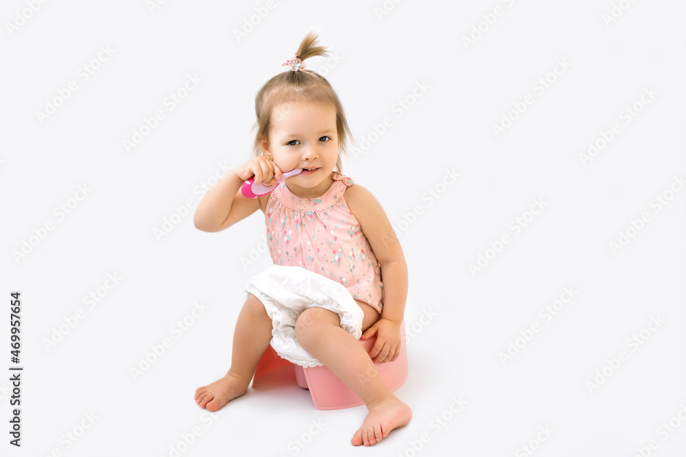 Сute girl is brushing teeth with a toothbrush while sitting on a potty ...