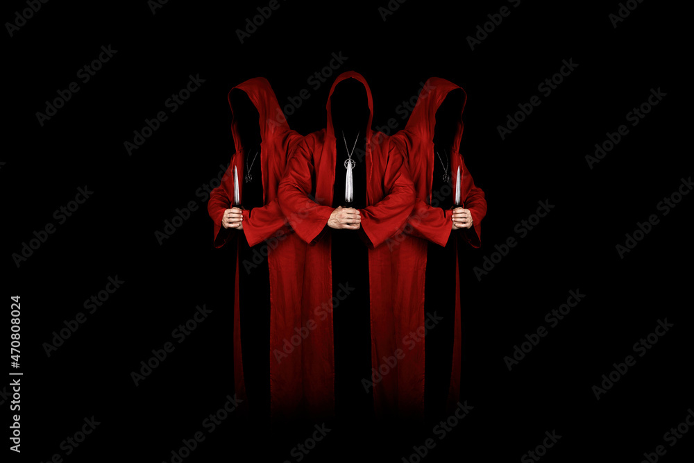 Mystery people in a red hooded cloaks in the dark holding ritual ...