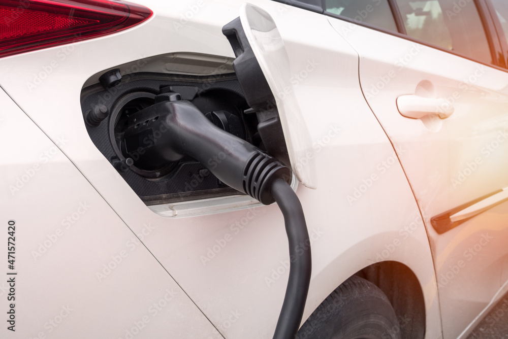 Power supply plugged into an electric vehicle at a charging station ...