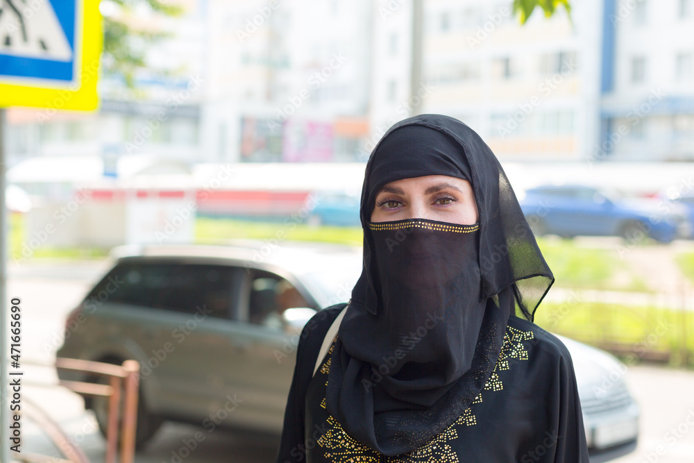 Portrait of a Muslim woman in a burqa in summer on city street near ...