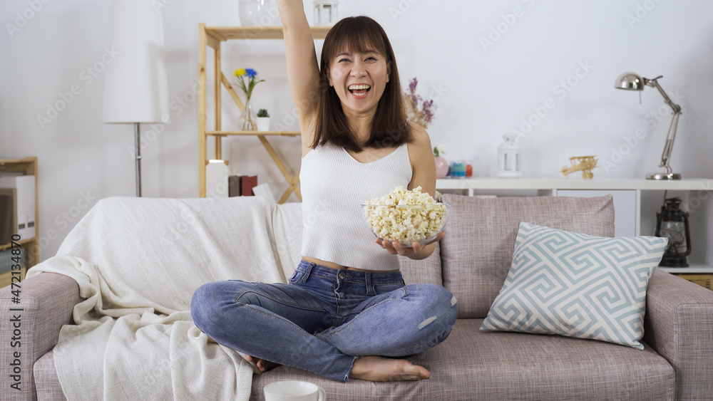 excited asian female staring at tv screen and holding popcorn while ...