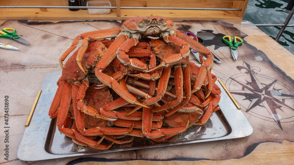 Boiled snow crabs are piled up on a metal tray on a yacht. Bright red ...
