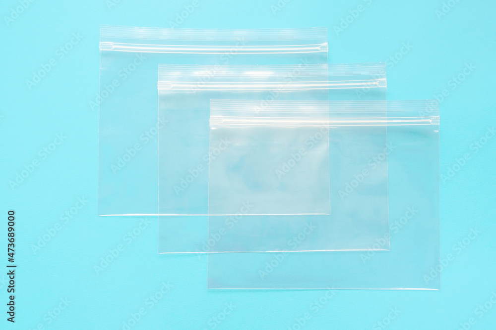 Three plastic bags with zip lock fasteners on blue background close-up ...