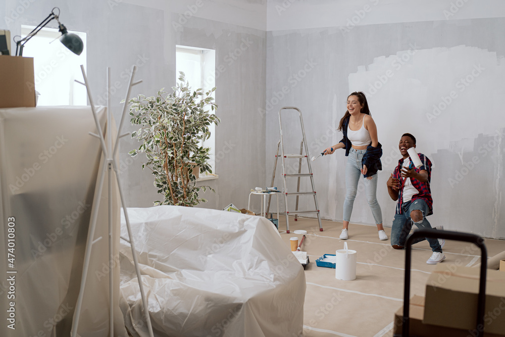 Smiling, cheerful friends are having fun while renovating, finishing ...