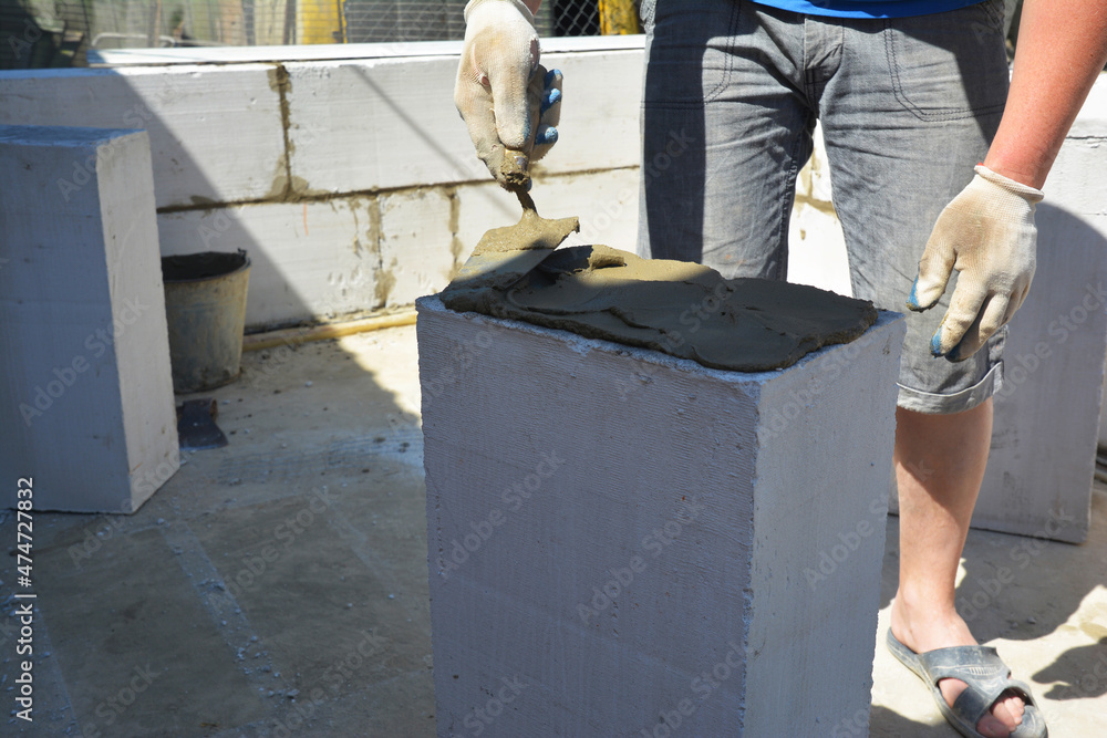 Building a concrete block wall. The contractor is laying concrete ...