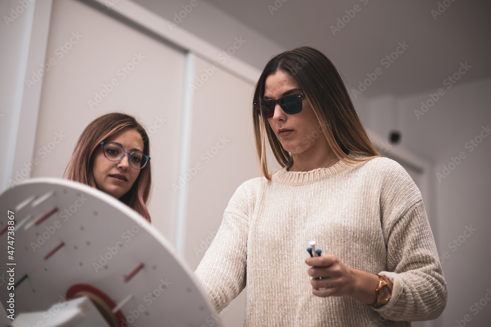 A woman undergoes vision therapy at an optician because she has visual ...