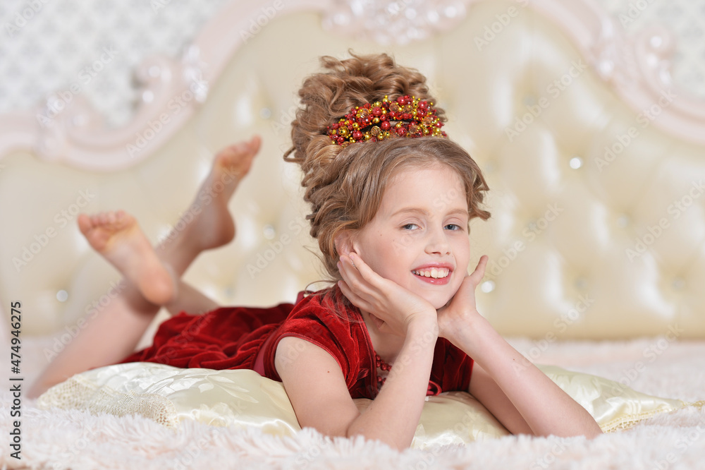 Foto de Stock cute little girl in red dress lying on bed | Adobe Stock